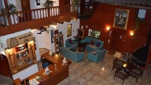 Um saguão de hotel com área de bar, assentos e uma escadaria.