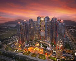 Um edifício alto com vários andares, um elemento circular central e uma área ajardinada ao redor.