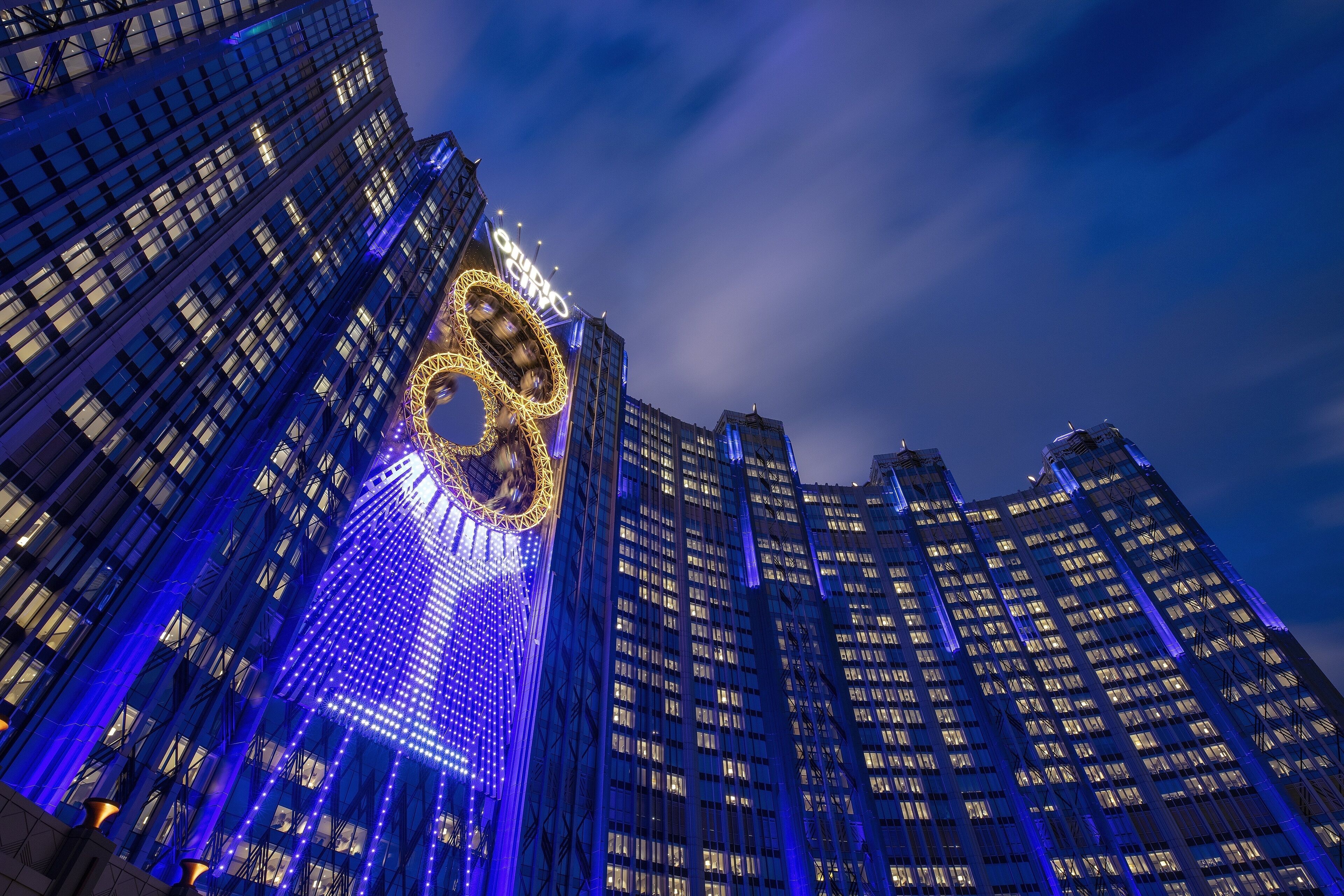 Um edifício alto com letreiros iluminados e um elemento de design circular marcante.