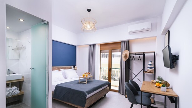 Quarto de hotel moderno com cama, escrivaninha, cadeira, varanda e banheiro.