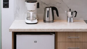 Uma cozinha com armários de madeira, cafeteira, chaleira e mini-geladeira.