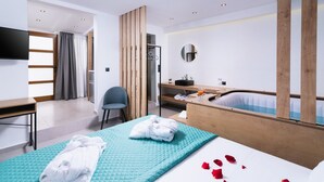 Quarto de hotel moderno com cama, escrivaninha, cadeira, televisão, banheiro e um espelho grande.