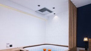 Um banheiro moderno com banheira de hidromassagem no canto, móveis de madeira e uma toalha em um banquinho.