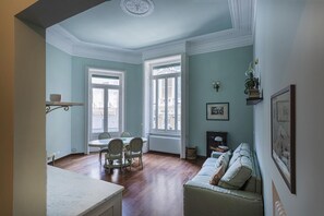 Uma sala de estar espaçosa com área de jantar, janelas amplas e um ambiente aconchegante.