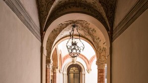 Um corredor com arcos e um candelabro.