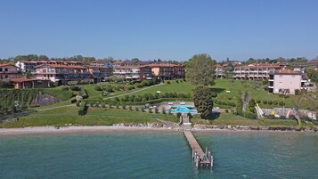 Um hotel à beira-mar com vários edifícios, piscina e um cais que se estende sobre a água.