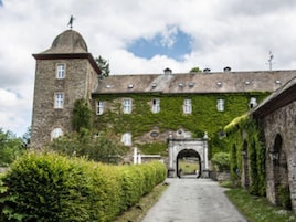 Um edifício histórico com uma torre, um arco e um caminho que leva à entrada.