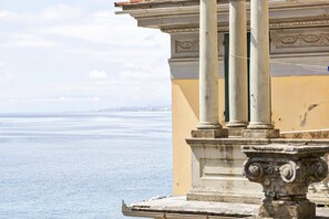 Estrutura arquitetônica clássica, com colunas e vista para o mar.