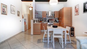 Uma cozinha moderna com armários brancos, uma mesa de jantar com cadeiras e um lustre.