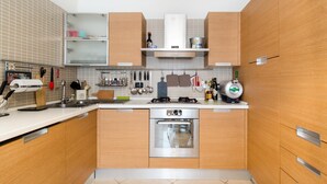 Uma cozinha moderna com armários de madeira, forno de aço inoxidável e diversos utensílios e eletrodomésticos.