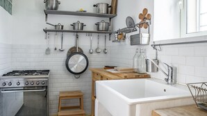 Cozinha com fogão, forno, pia e banquetas de madeira.