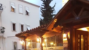 Uma área de estar acolhedora ao ar livre, com cadeiras e mesa de madeira, uma pérgola de madeira e uma placa com o nome 'Limon Hotel'.