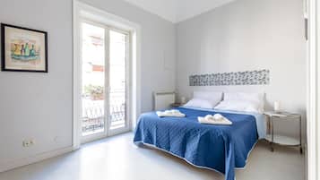 Um quarto com uma cama, mesa de cabeceira, radiador, janela e porta.