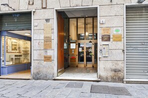 Entrada de um edifício com vários anúncios comerciais, uma porta visível e calçada de azulejos.