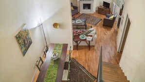 Uma sala de estar ampla com lareira, um sofá, uma mesa de centro e uma mesa de jantar com um caminho de mesa verde.