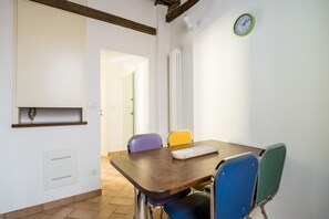 Quarto com mesa de madeira, duas cadeiras, relógio na parede e radiador.