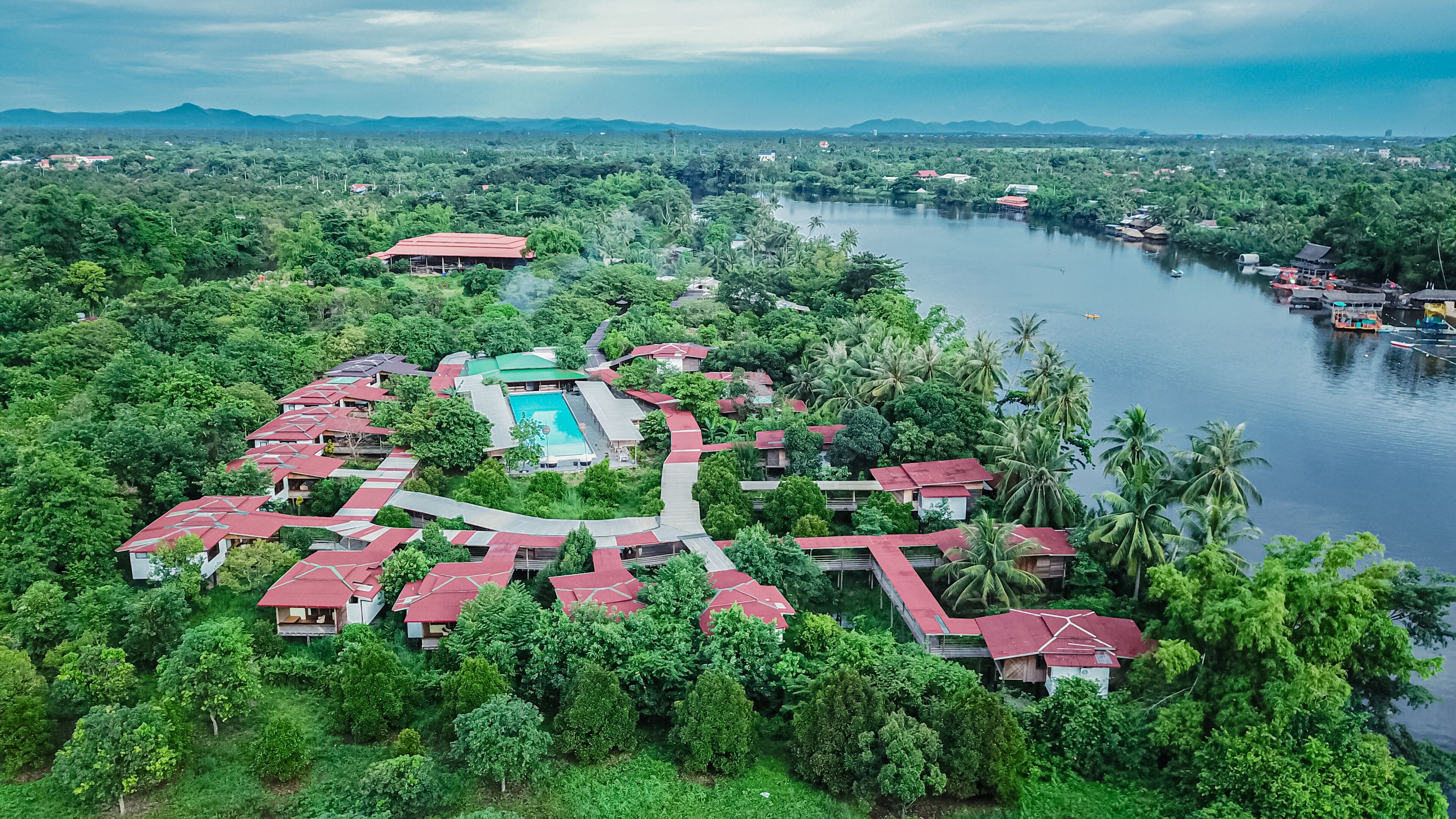Vista aérea de um resort com vários edifícios, piscina e um rio.