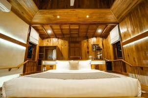 Quarto estilo cabana de madeira com uma cama grande, paredes de madeira e teto de madeira.