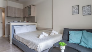 Quarto de hotel moderno com cama, sofá, uma mesinha com uma planta e obras de arte na parede.
