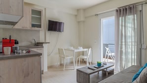 Cozinha moderna com área de refeições, uma pequena mesa com cadeiras e varanda com uma cadeira.