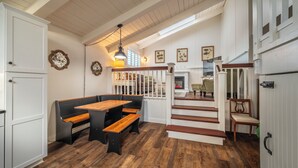 Uma área de refeições com mesa e bancos de madeira, uma escada com corrimão e uma lareira.