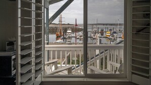 Vista de um quarto com varanda sobre uma marina com barcos.