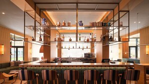 Uma área de bar moderna com ilha central, banquetas e prateleiras com garrafas e objetos decorativos.