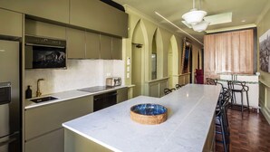 Cozinha moderna com ilha de mármore, eletrodomésticos embutidos e área de refeições com banquetas.