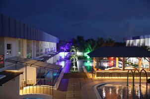Um hotel moderno com área de piscina, espaço para sentar ao ar livre e escadaria que dá acesso aos andares superiores.