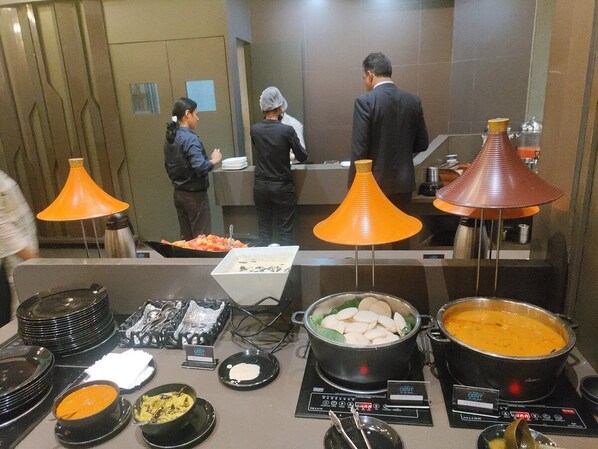 Buffet montado com diversos pratos, incluindo uma panela grande de sopa e uma tigela de arroz.