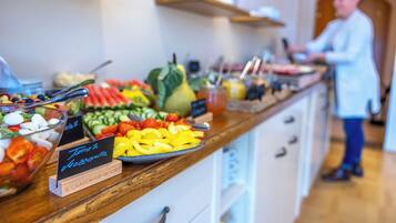 Buffet com diversas frutas e legumes, um letreiro indicando 'Time to Mozzarella' e uma pessoa em casaco branco ao fundo.