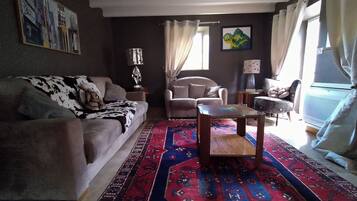 Uma sala de estar com sofá, poltrona, mesa de centro e tapete estampado.