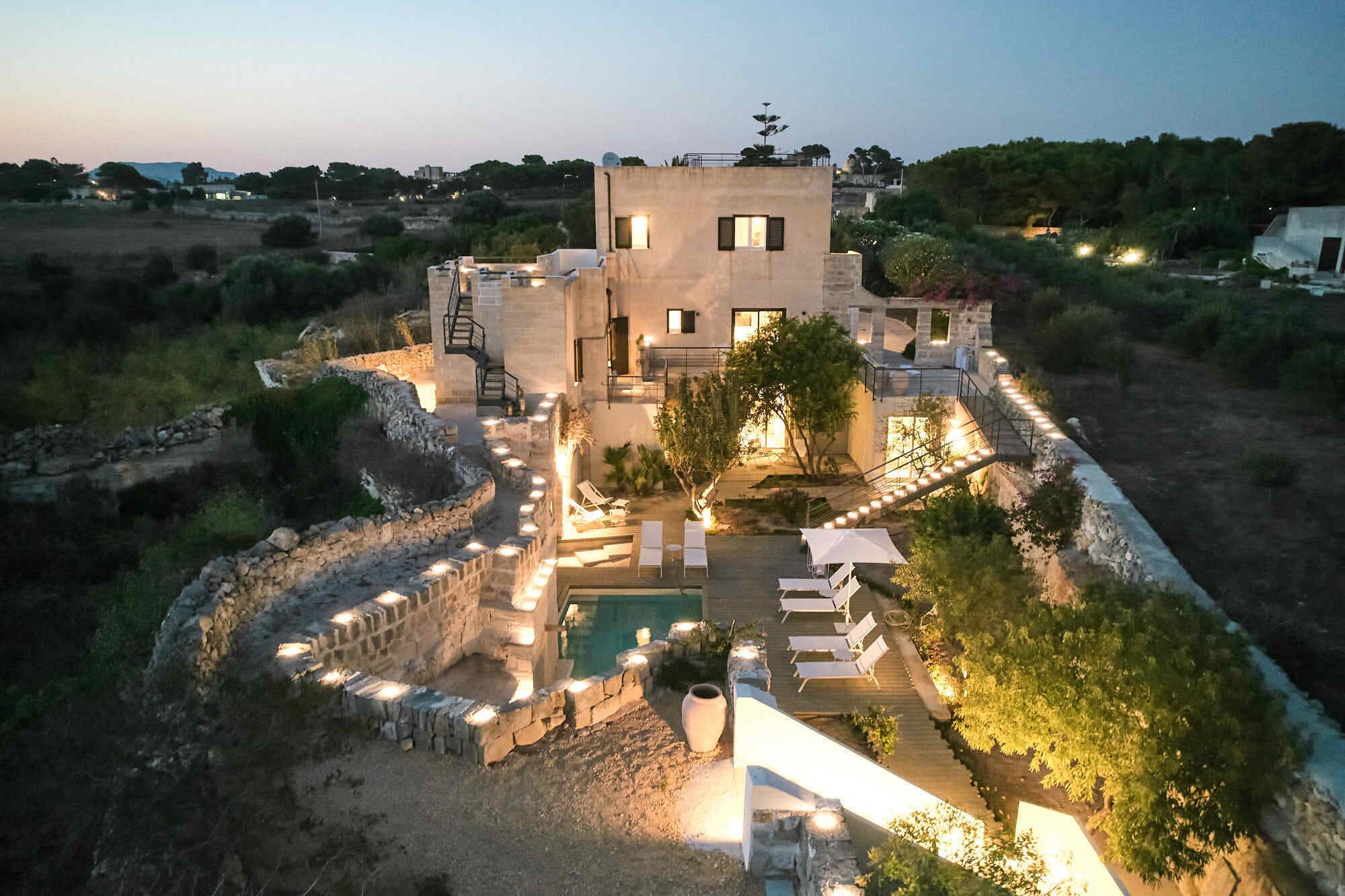 Uma villa moderna com piscina, área de estar externa e um muro de arrimo de pedra.
