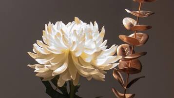 Uma flor branca num vaso com um detalhe decorativo cor de cobre.