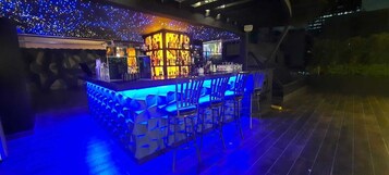 Uma área de bar com balcão, banquetes e um lustre decorativo.