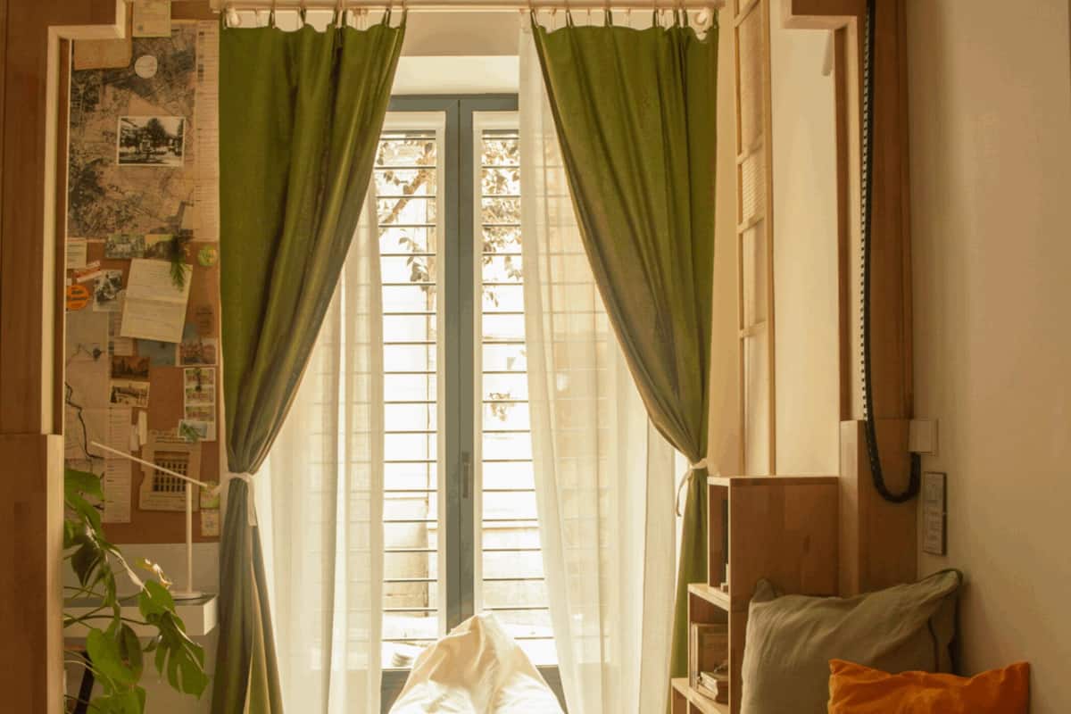 Um quarto aconchegante com teto de madeira, uma poltrona de feijão, uma pequena mesa e uma estante de livros.