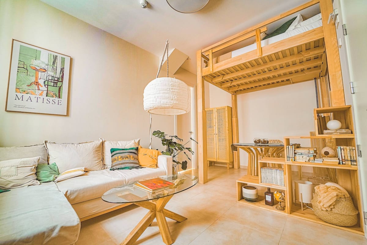 Uma sala de estar aconchegante com um sofá branco, uma mesa de centro de vidro e uma estante de madeira.