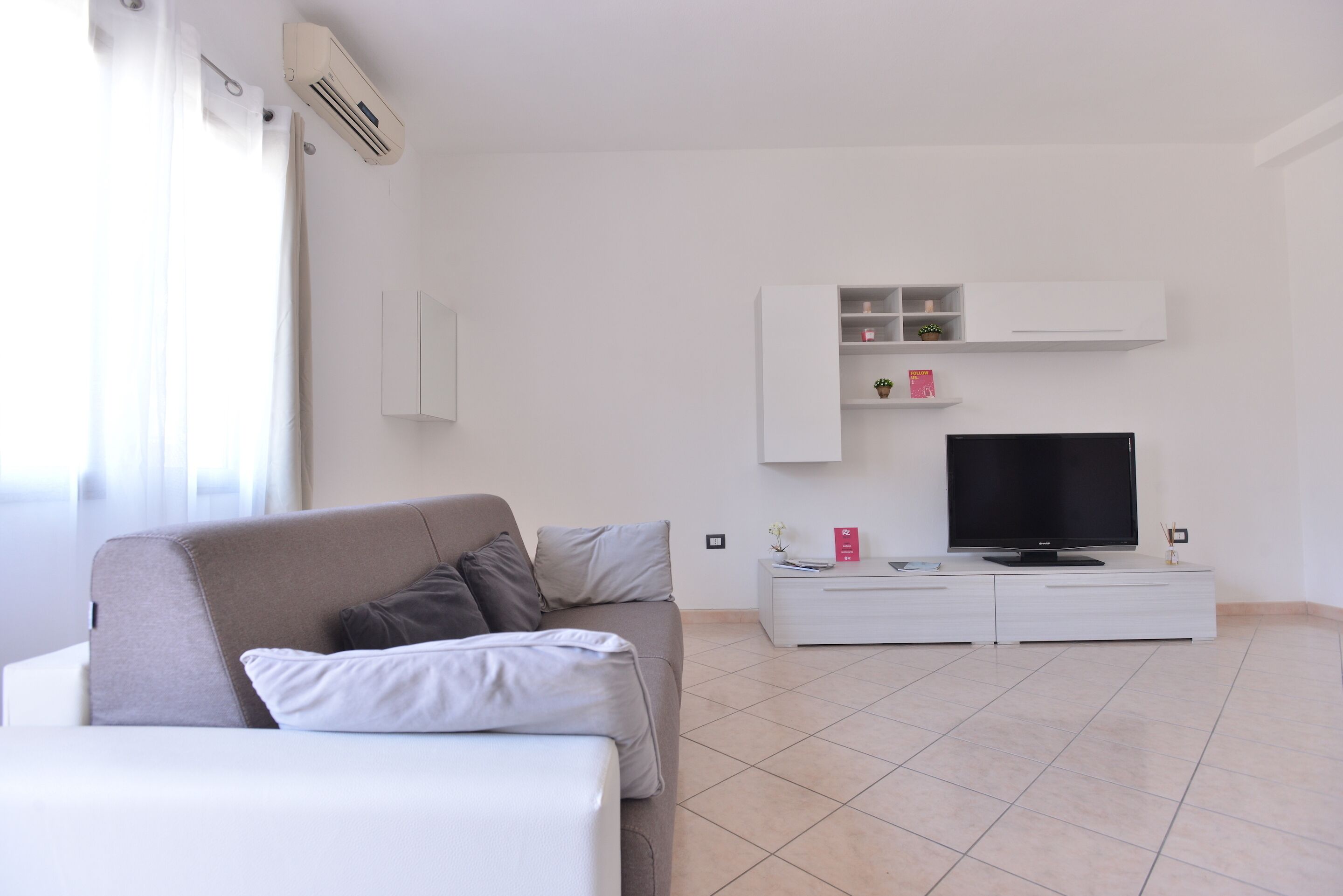 Uma sala de estar moderna com sofá, televisão e unidade de armazenamento.