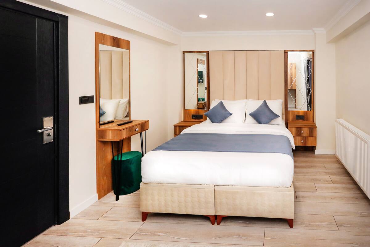 Quarto moderno com uma cama grande, duas mesas de cabeceira, um penteado e um espelho.