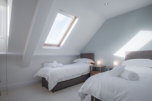 Quarto moderno com duas camas, um claraboia e uma mesa de cabeceira com abajur.