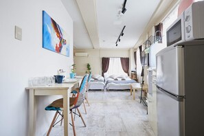 Cozinha moderna com frigorífico, micro-ondas e área de refeições com cadeiras e mesa.