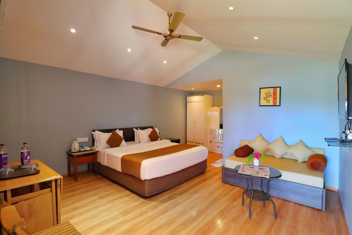 Quarto de hotel com uma cama grande, um sofá, uma escrivaninha e um ventilador de teto.