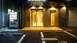 Entrada de hotel com máquina de vendas automática, portas duplas e um letreiro sobre elas.