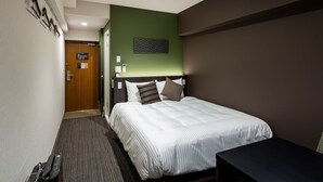 Quarto de hotel com cama, mesa de cabeceira e escrivaninha.