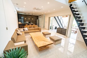 Uma sala de estar ampla com sofás, uma mesa de centro de madeira e uma escada com design moderno.