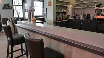 Uma área de bar com balcão, banquetas e diversas garrafas e copos em prateleiras.