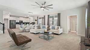 Uma sala de estar moderna com um sofá seccional, uma mesa de centro de vidro e uma poltrona de couro marrom.
