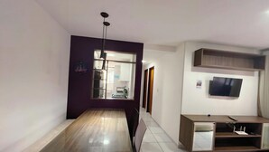 Uma sala de estar moderna com uma mesa de jantar, uma TV montada na parede e um móvel planejado para entretenimento.