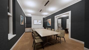 Uma sala de conferências moderna com uma mesa comprida, cadeiras e uma escada ao fundo.