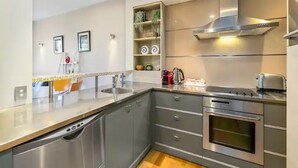 Uma cozinha moderna com armários cinzas, eletrodomésticos de aço inoxidável e forno embutido.